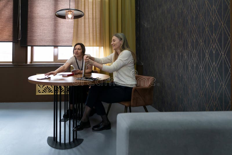 Discussion between Two Women at a Table in a Modern Office Setting in ...