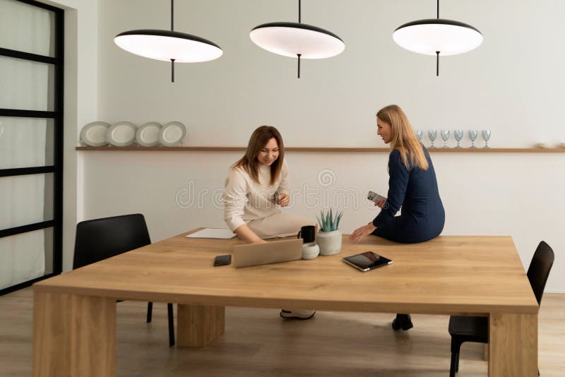 Two Women Engaged in a Creative Discussion at a Modern Wooden Table in ...