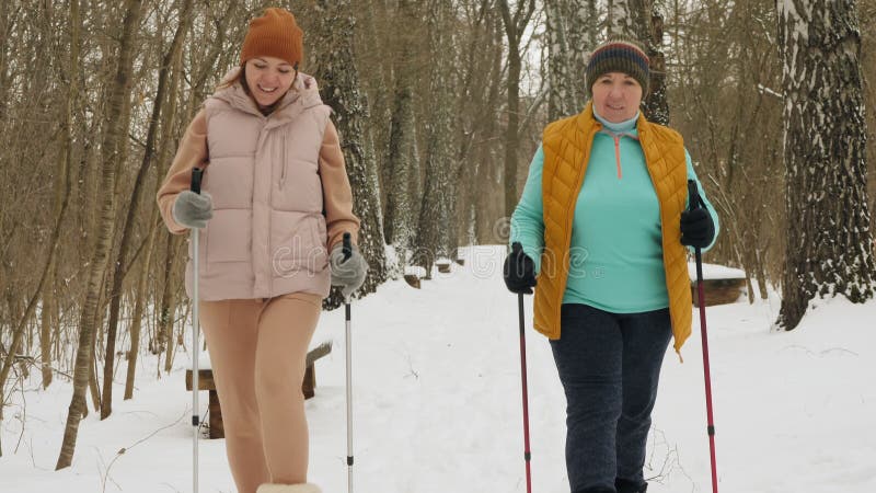 Two Women are Engaged in Nordic Walking in Winter. Close Up Legs only ... Two Women are Engaged in Nordic Walking in Winter. Close Up Legs only ...