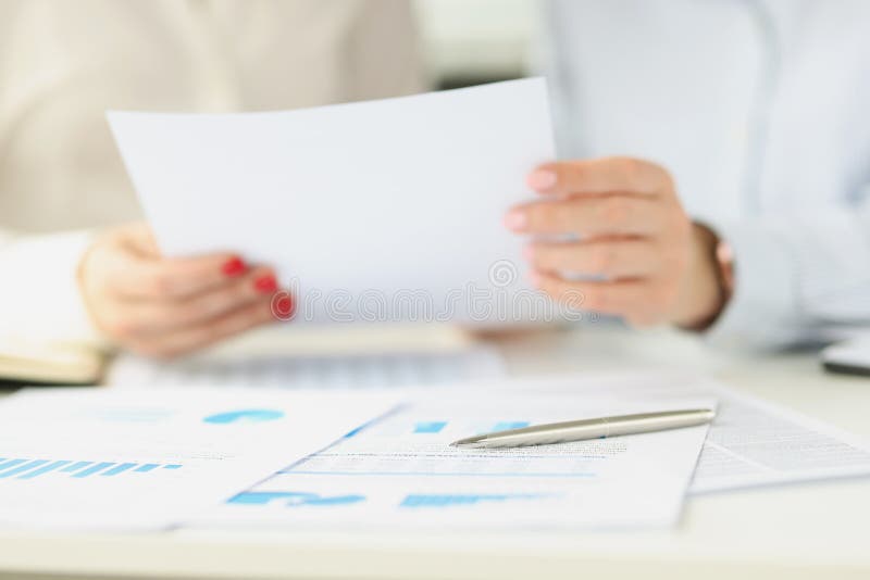 Two Women Hold a Document on Table Lie Charts with Business Indicators ...