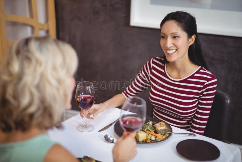 Two Women Interacting and Smiling while Painting Walls White with Paint ...