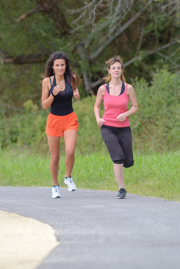 Two women jogging outdoors stock image. Image of stamina - 241702149