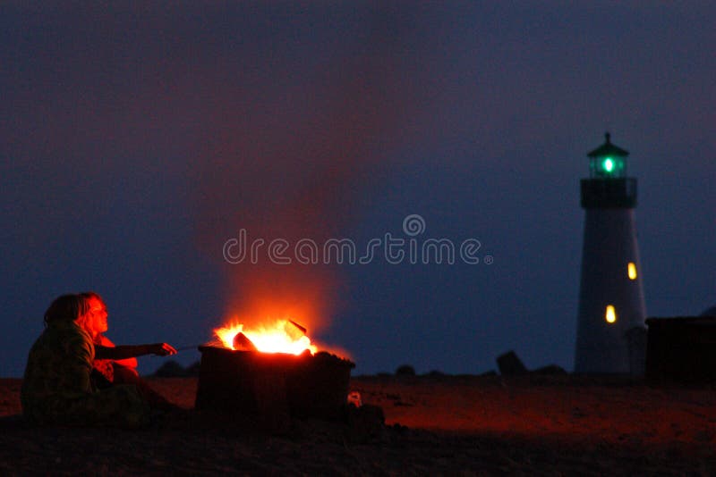 Two Women Keep a Fire Going within Sight of a Lighthouse Editorial ...