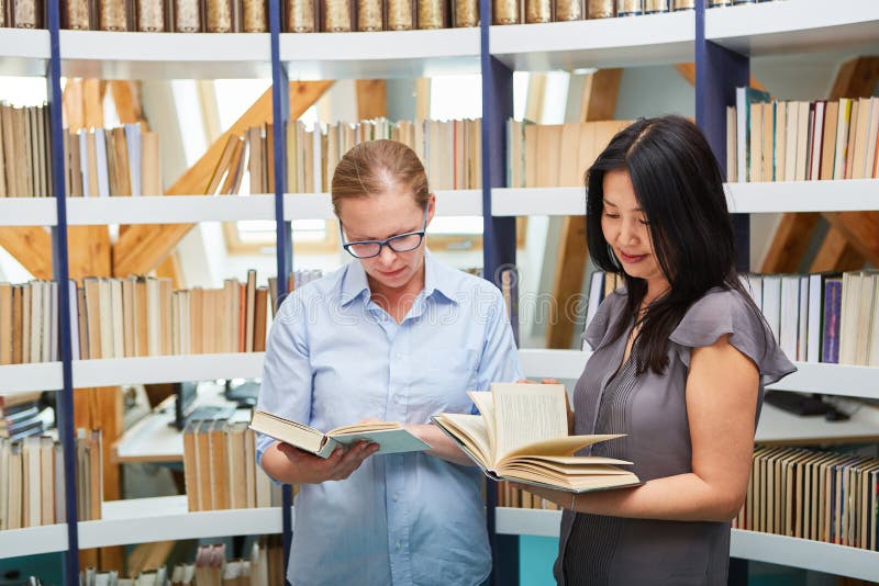 Two Women in a Library Reading the Book Stock Image - Image of ...