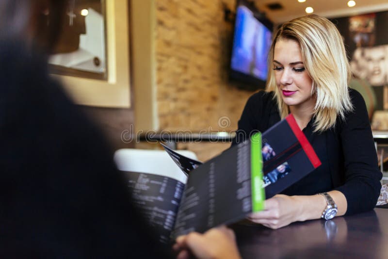 Two Friends in a Cafe Looking at the Menu Stock Image - Image of ...