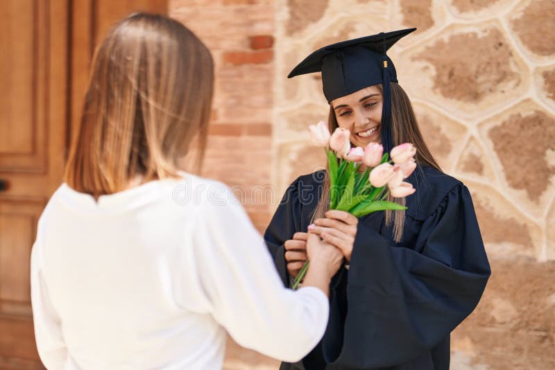 Two Women Mother And Graduated Daughter Holding Flowers At Campus
