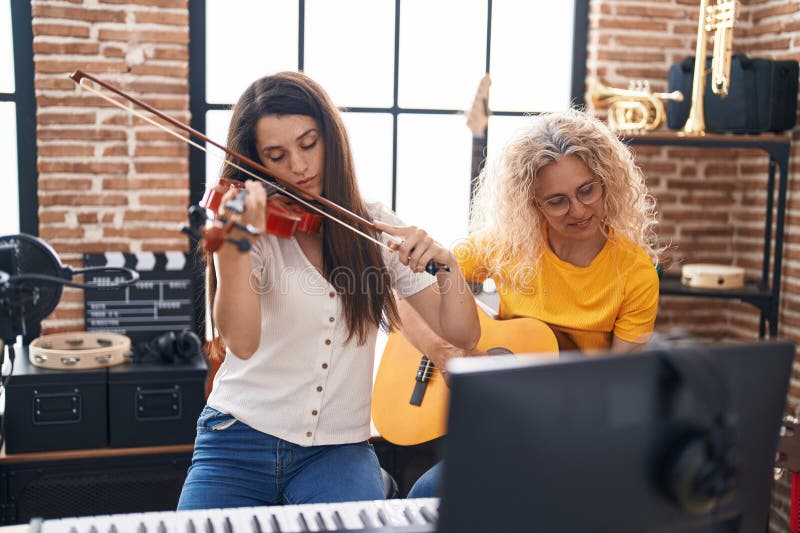 Two Women Musicians Playing Violin and Classical Guitar at Music Studio ...