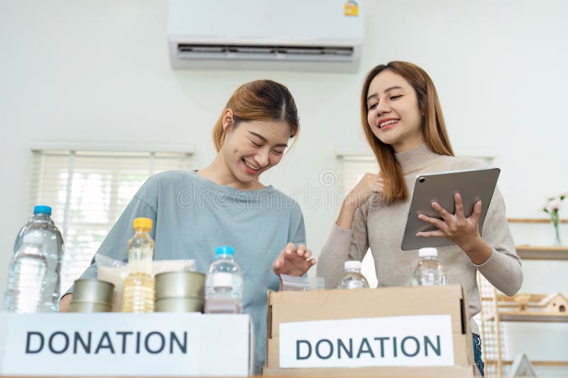 Two Women Organizing Donate in Boxes with Labeled Signs in a Bright ...