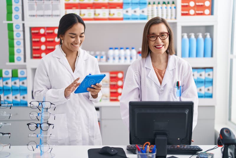 Two Women Pharmacist Using Computer and Touchpad Working at Pharmacy ...