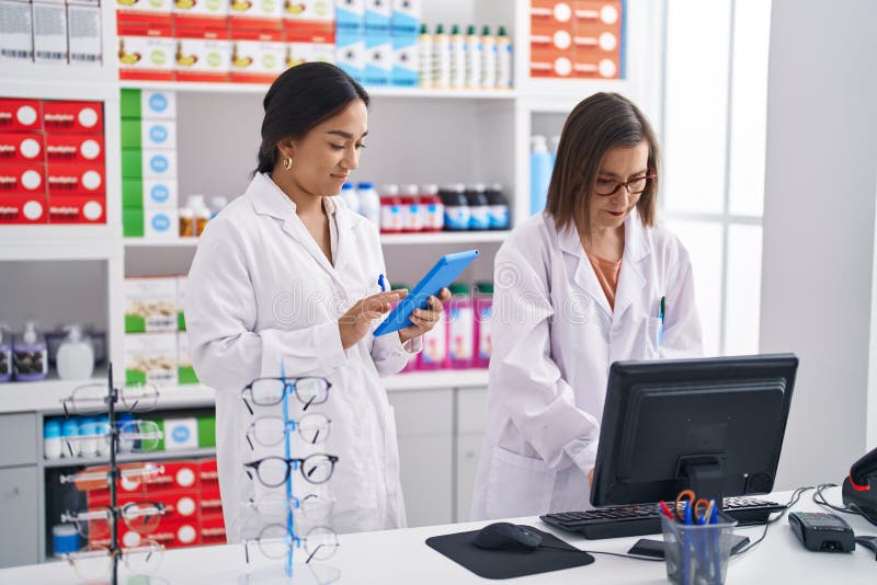 Two Women Pharmacist Using Computer and Touchpad Working at Pharmacy ...