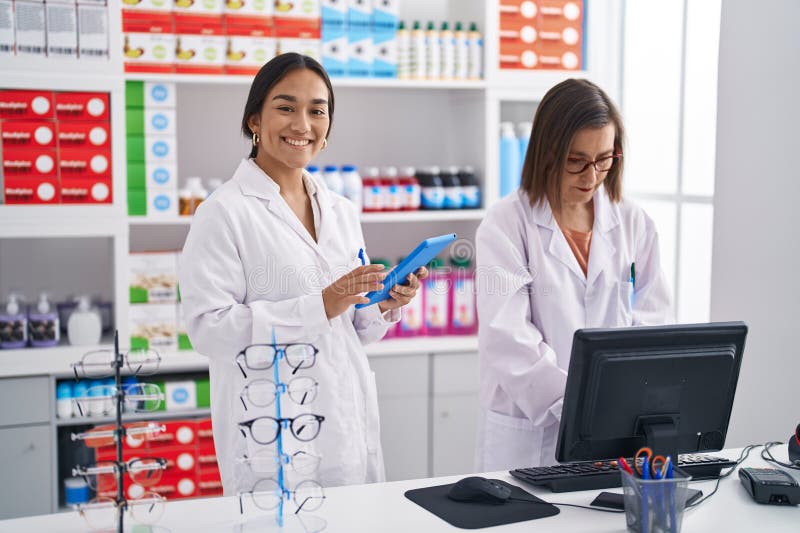 Two Women Pharmacist Using Computer and Touchpad Working at Pharmacy ...