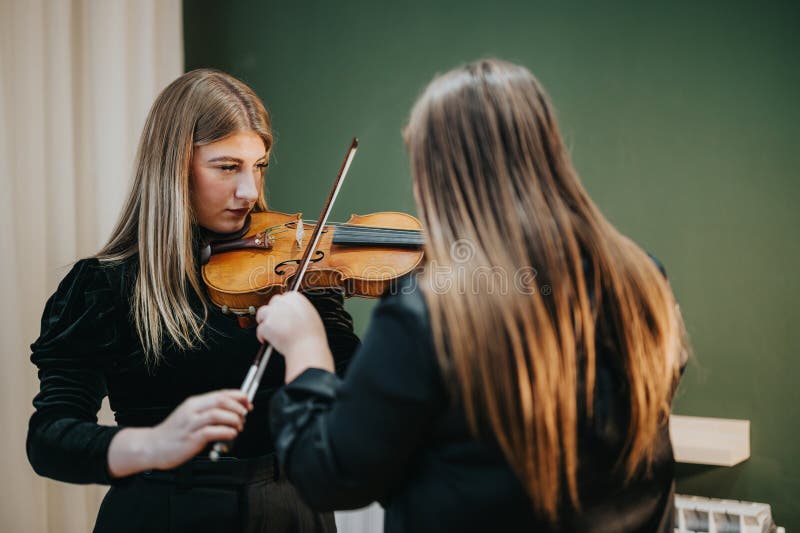 Two Women Practicing Violin in a Music Class with Focused Expressions ...