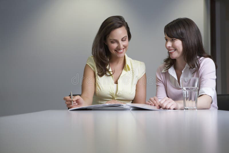 Two Women Reading Papers at Desk Stock Photo - Image of water ...