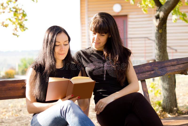 Two women reading together stock image. Image of outdoors - 27036059