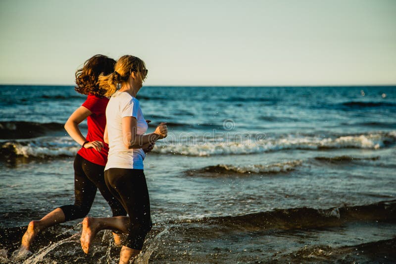 Two women running on beach stock image. Image of adult - 124921403