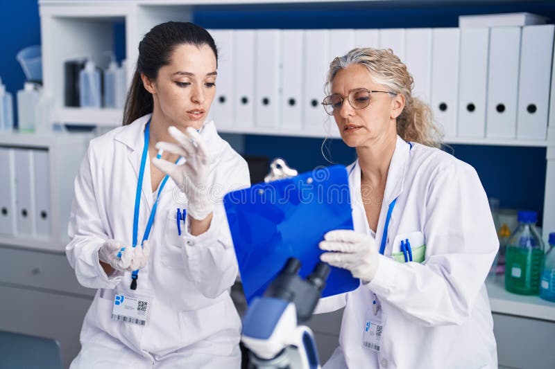 Two Women Scientists Holding Pills Write on Document at Laboratory ...