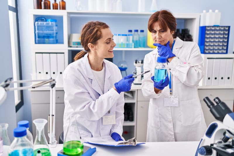 Two Women Scientists Holding Test Tube Writing on Document at ...