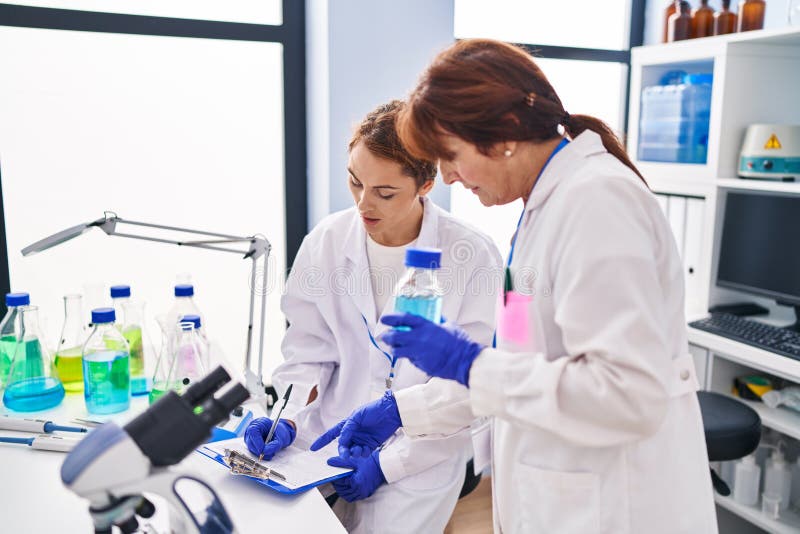 Two Women Scientists Holding Test Tube Writing on Document at ...