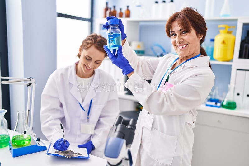Two Women Scientists Holding Test Tube Writing on Document at ...