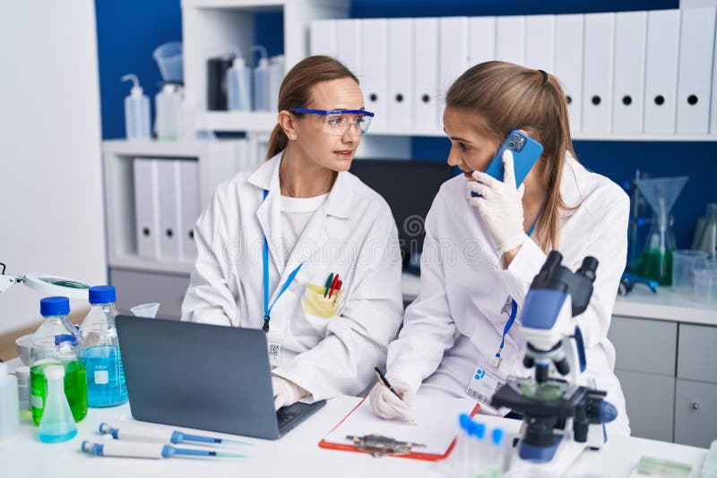 Two Women Scientists Talking on the Smartphone Working at Laboratory ...