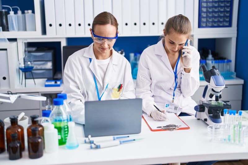 Two Women Scientists Talking on the Smartphone Working at Laboratory ...
