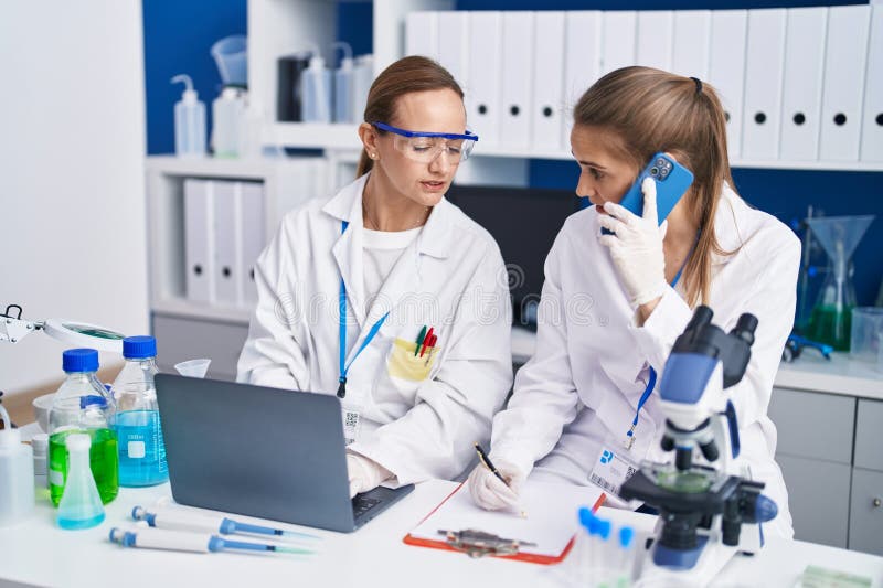 Two Women Scientists Talking on the Smartphone Working at Laboratory ...