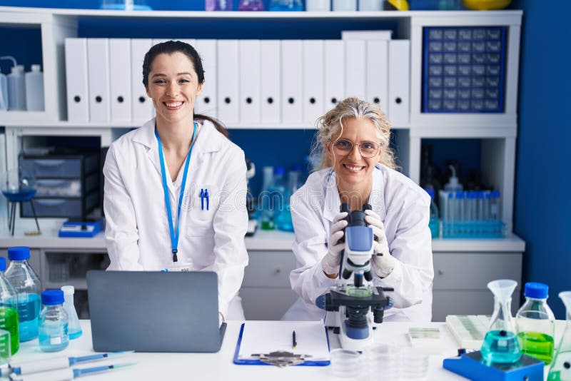 Two Women Scientists Using Microscope and Laptop at Laboratory Stock ...