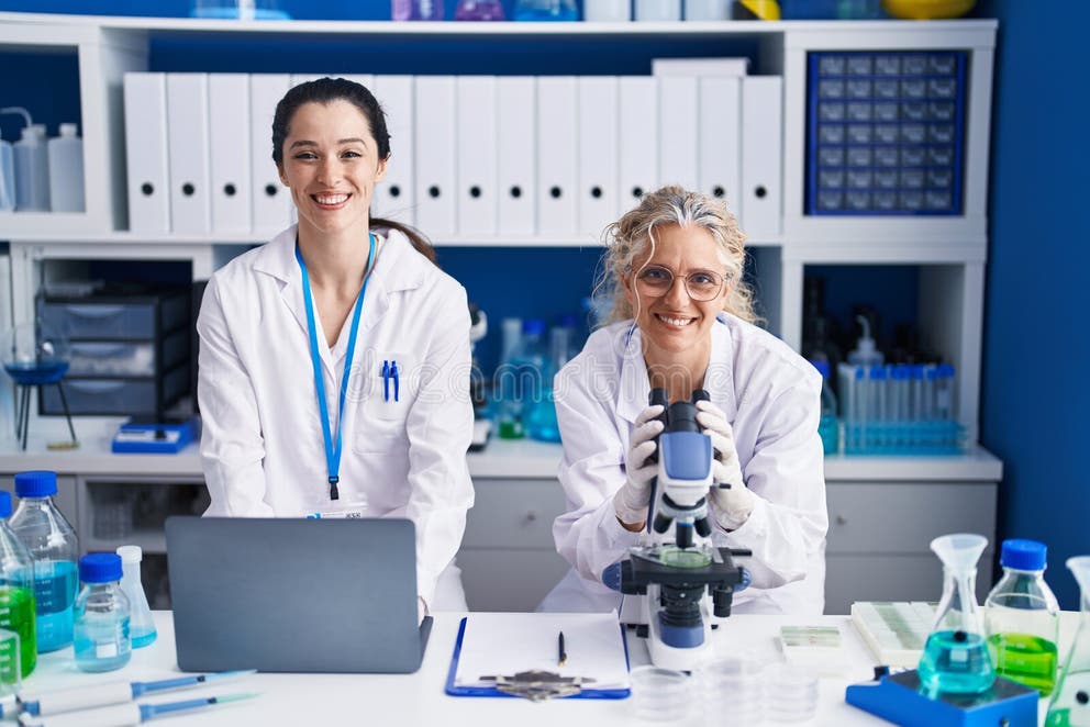 Two Women Scientists Using Microscope and Laptop at Laboratory Stock ...