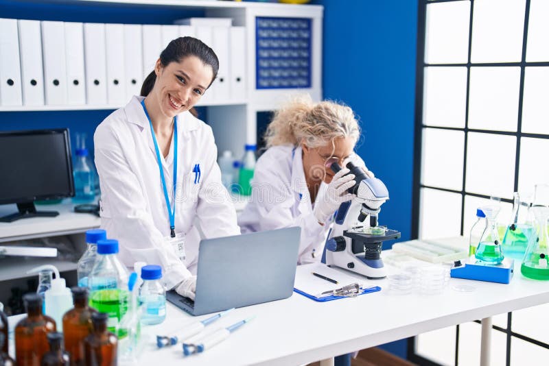 Two Women Scientists Using Microscope and Laptop at Laboratory Stock ...