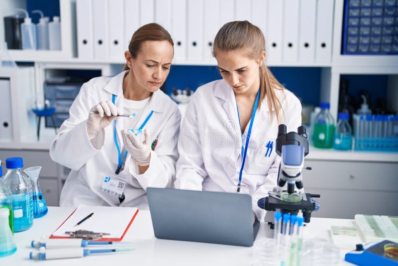 Two Women Scientists Using Microscope and Write on Document at ...