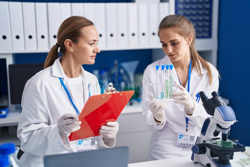 Two Women Scientists Write on Document Holding Test Tubes at Laboratory ...