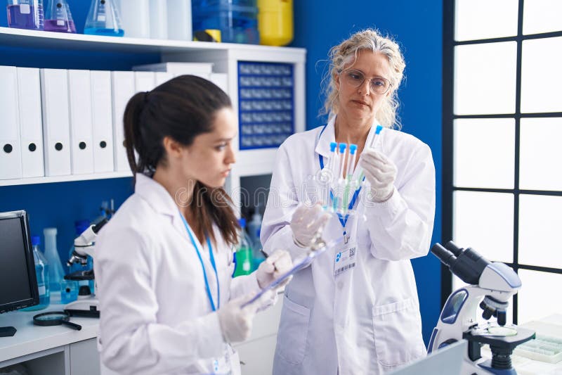 Two Women Scientists Writing on Document Holding Test Tubes at ...