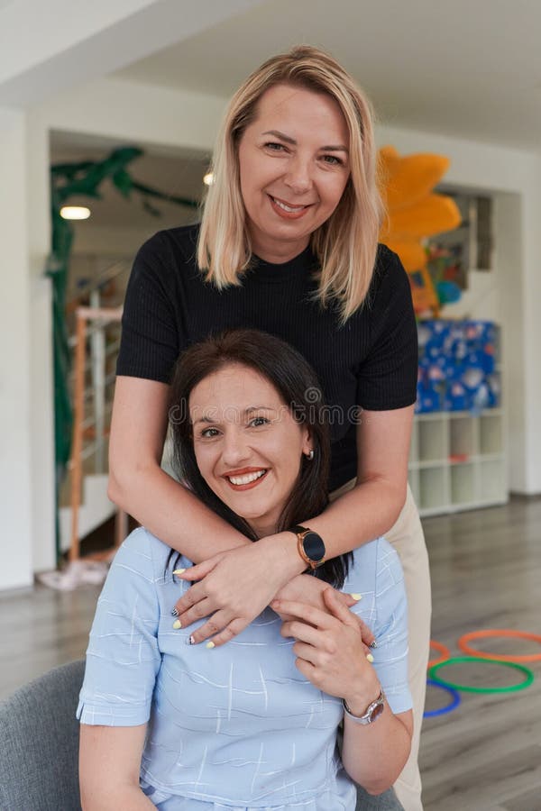 Two Women Share a Heartfelt Embrace while at a Preschool, Showcasing ...