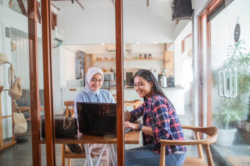 Two Women Sit Using a Laptop Computer Working Together Stock Image ...