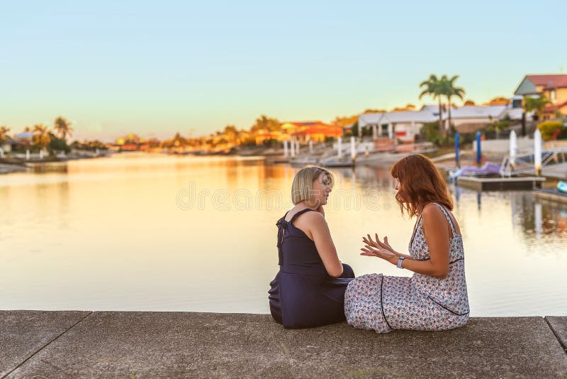 Two Women are Sitting on a River Pier and Discussing Stock Image ...