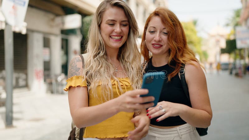 Two Women Standing Together Using Smartphone at Street Stock Photo ...