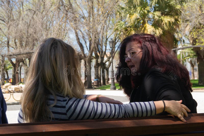 Two Women Talking and Gesturing on a Park Bench Stock Photo - Image of ...