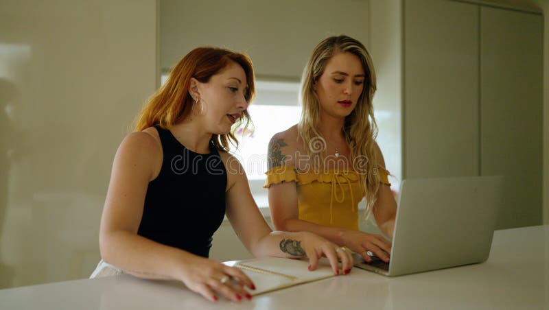 Two Women Using Laptop Writing on Notebook Sitting on Table at Kitchen ...