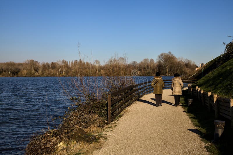 Two Women Walking on a Path by the Shore of a Lake at Sunset in Winter ...