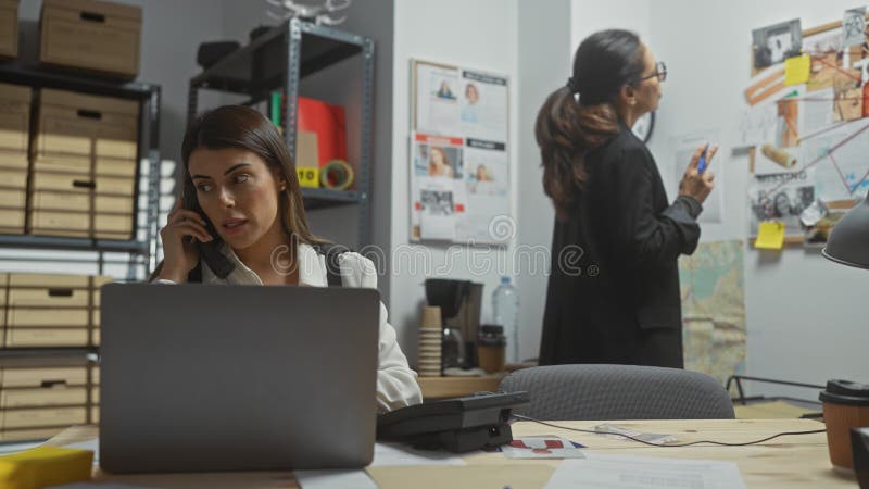 Two Women Working in a Busy Detective Office, with One on the Phone and ...
