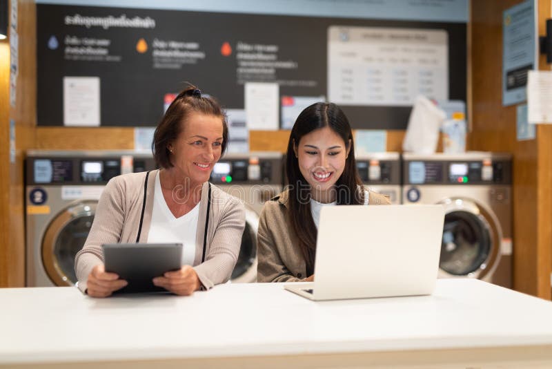 Two Women Working on a Computer in Laundry Shop Stock Photo - Image of ...