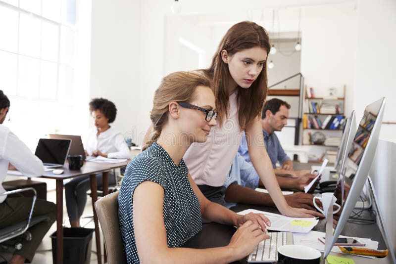 Two Women Working Together at Computer in Open Plan Office Stock Photo ...