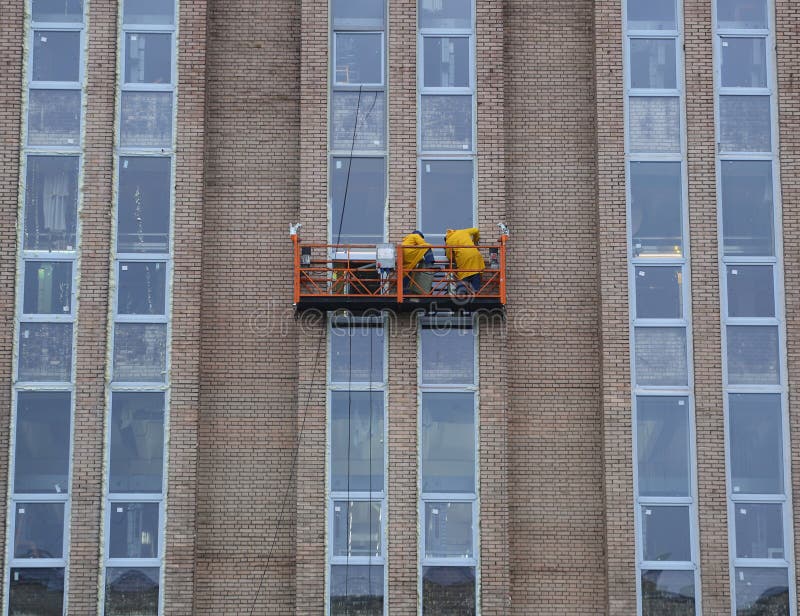 Two Workers in a Construction Cradle on a Brick Wall of a House Stock ...