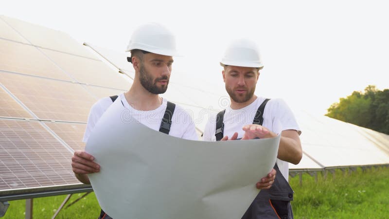 Two Workers Engineers Talking with Each Other while Holding a Blue ...
