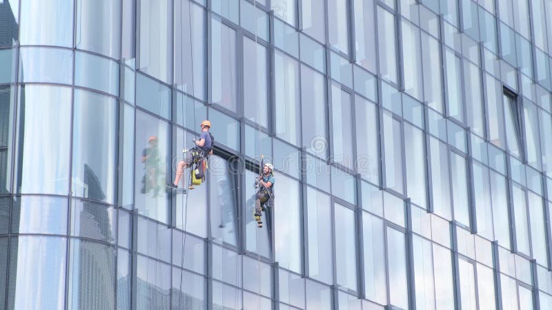 Two Workers Have Windows in a Tall Skyscraper Hanging on a Lifeline ...