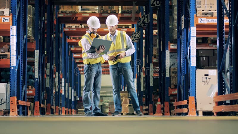 Storeman in Uniform Typing on Laptop among Warehouse Shelves Stock ...