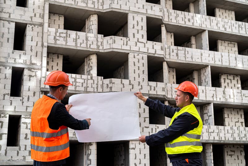 Two Workers in Overalls and Helmets Developed a Construction Plan for ...