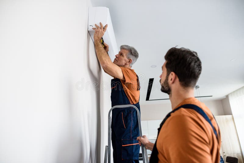 Two Workers in Uniform, Air Conditioning Masters Using Ladder while ...