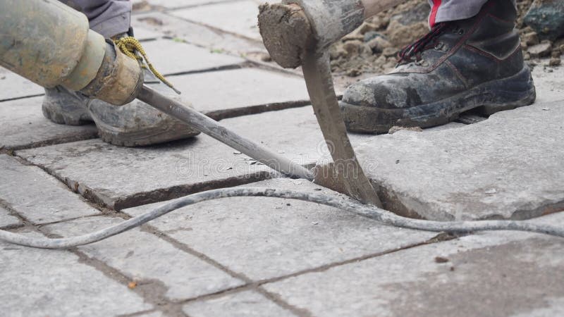 A Construction Worker Using a Jackhammer To Break Concrete Outdoors in ...