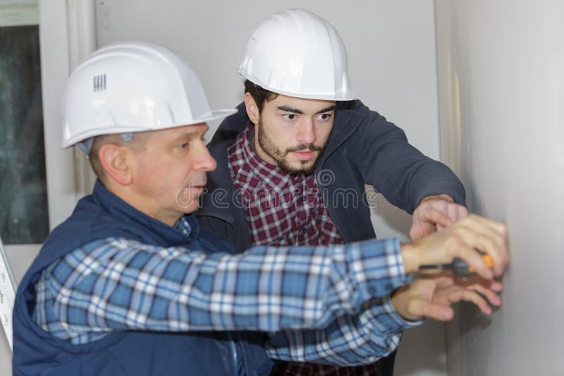 Two Workmen Measureing Wall Stock Image - Image of hardhat, builder ...